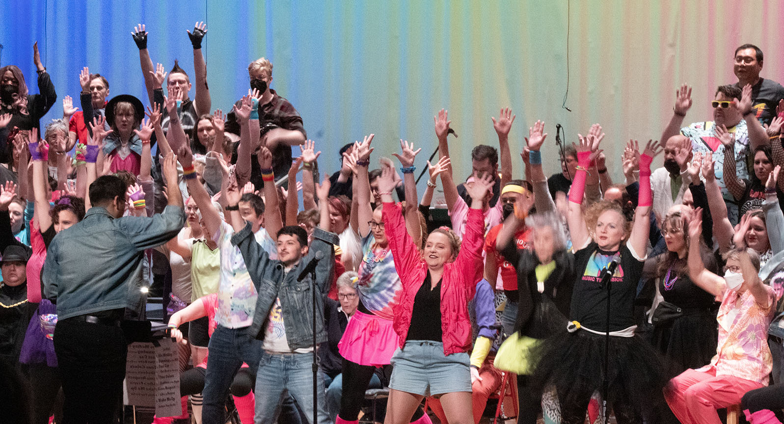 The Out Loud Chorus raise their hands and dance during their ...